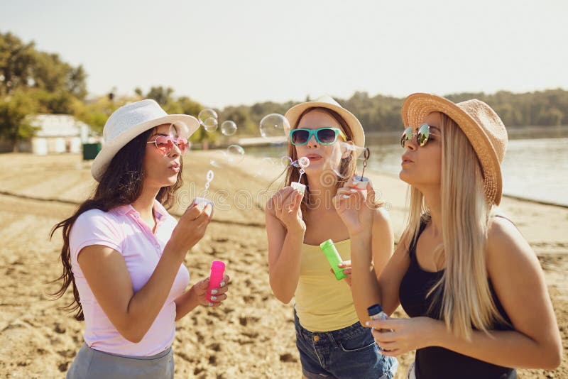 Amiche Che Soffiano Le Bolle Di Sapone Sulla Spiaggia Fotografia Stock