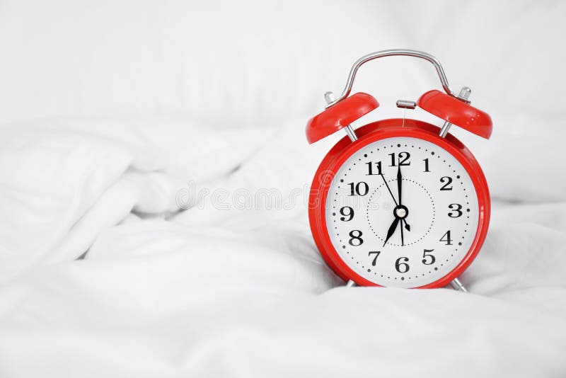Analog alarm clock on bed stock photo. Image of bedroom - 120707480