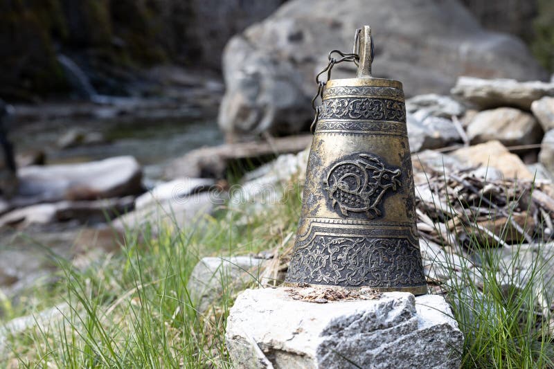 An Ancient Metal Bell with a Pattern Stands on a Stone on the Bank of a ...