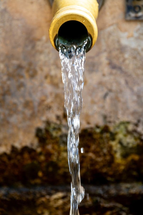 Ancient Spout Pouring Water into Stone Basin with Sunlight Reflection ...