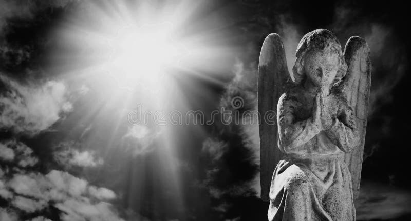 Ancient Statueof Angel in Rays of Light Against Sky with Clouds. Black ...