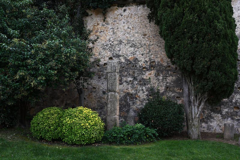 Ancient Stone Column in a Serene Garden with Greenery and Rustic Wall ...