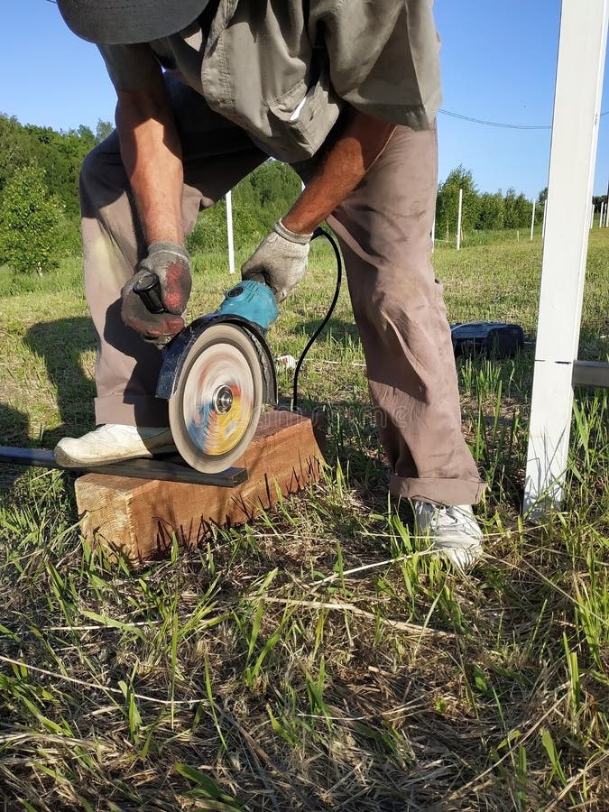 A Man In The Yard Cuts The Metal Profile On The Fence Standing On The ...