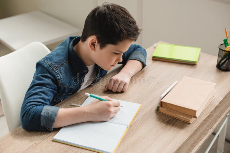 Angle View of Attentive Boy Writing in Copy Book while Doing Schoolwork ...