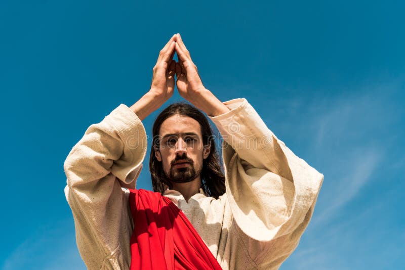 Angle View of Jesus with Praying and Looking at Camera Against Blue Sky ...