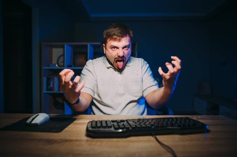 An Angry Adult Man with a Beard Sits at Night at the Computer at Work ...