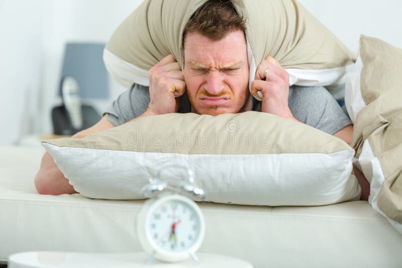Angry Man Lying in Bed with Pillow on Head Stock Photo - Image of noisy ...