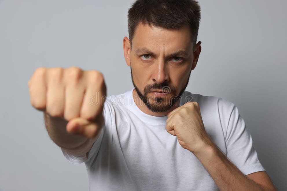 Angry Man Throwing Punch on Grey Background Stock Photo - Image of hand ...