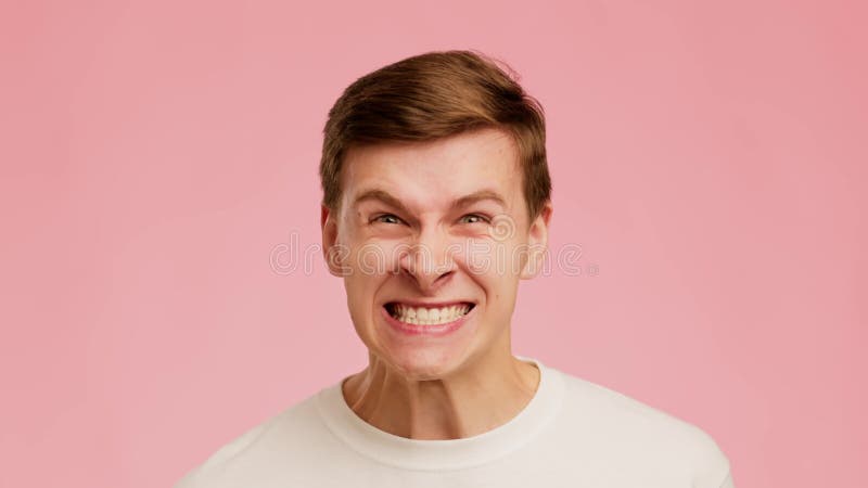 Angry Millennial Man Clenching Teeth Expressing Aggression Over Pink
