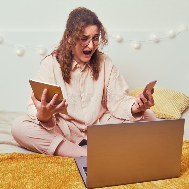 An Angry Woman Screams with Gadgets in Her Hands on a Home Bed ...