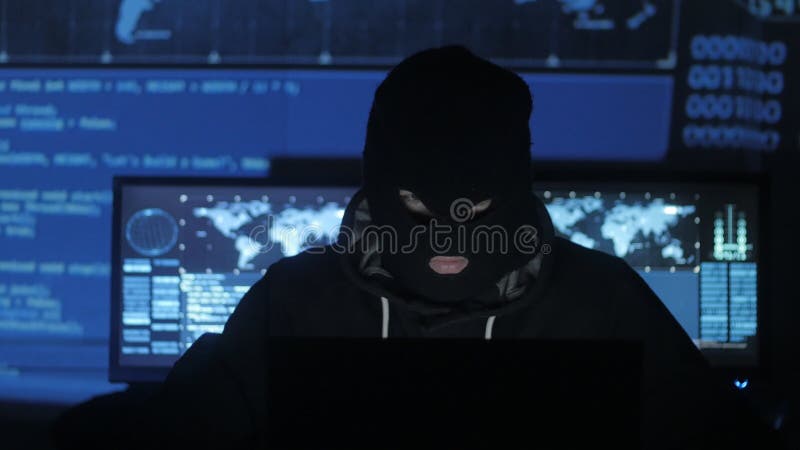 Anonymous Hacker in the Mask Tries To Enter the System Using Codes and Numbers To Find Out the ...