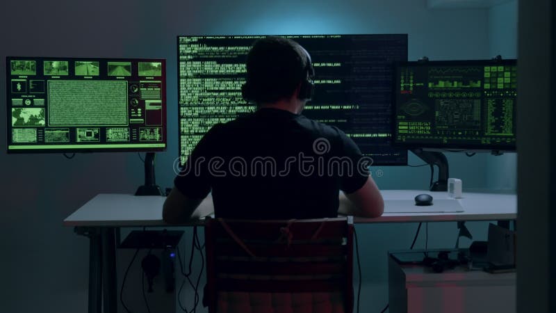 Anonymous Male Hacker from Behind with Headphones in Front of Several ...