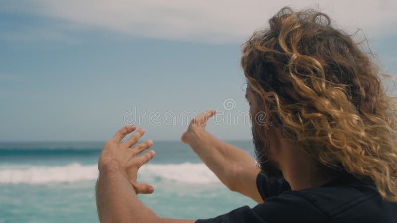 Anonymous Man With Long Curly Hair Stay On Ocean Beach Moving Hands As If Controlling Power Of