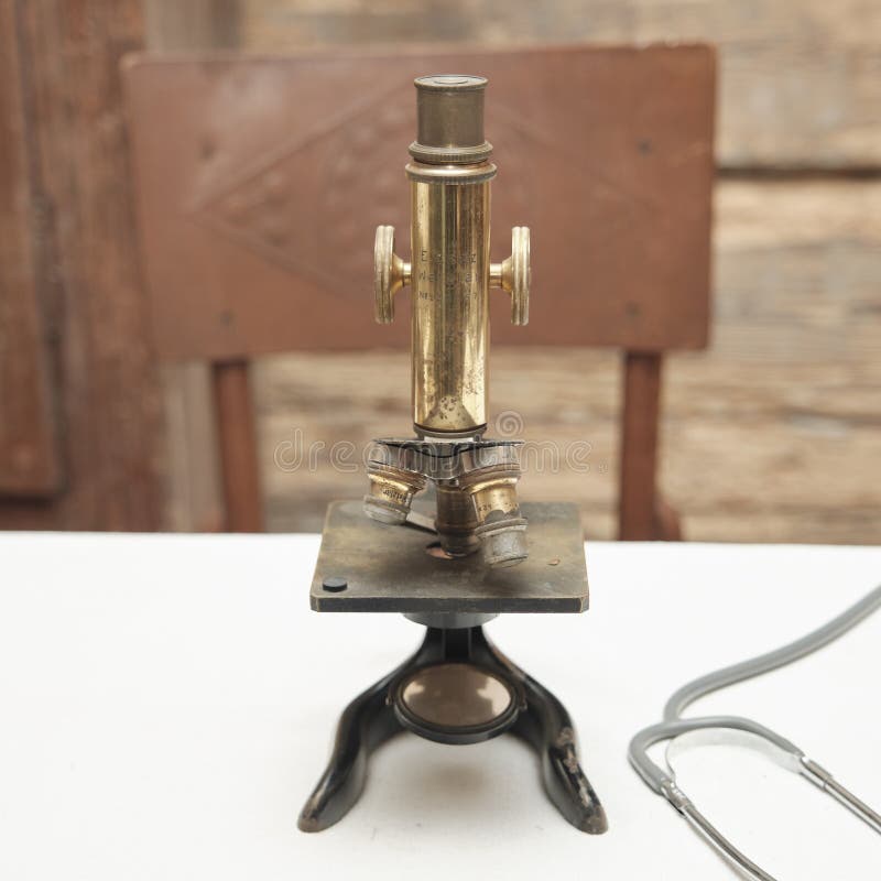 Antique Microscope Stands on a White Table Against the Wooden Wall of ...