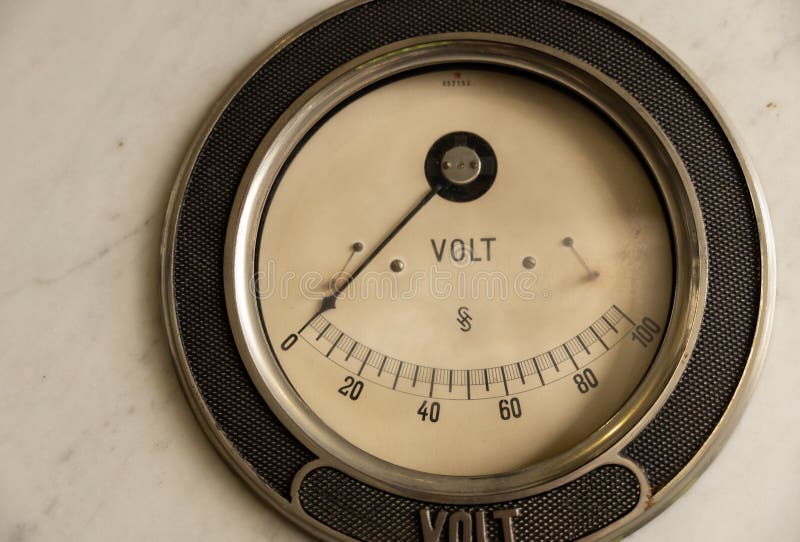 An Antique Non-functioning Voltmeter in a Round Frame Hangs on the Wall ...