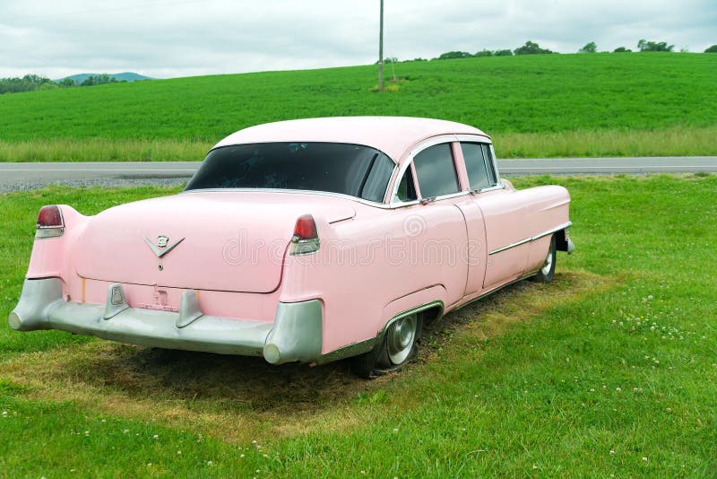 An Antique Pink Cadillac is Parked on the Grass Next To the Road ...