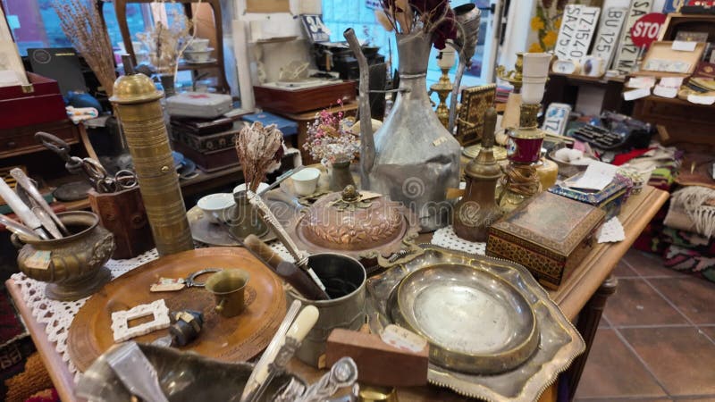 Antique Store Interior with a Table Full of Vintage Items, Including Silverware, Brass Ornaments ...