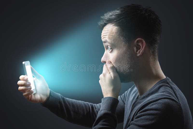 Appalled Man Looking at His Glowing Smartphone Screen Stock Photo ...