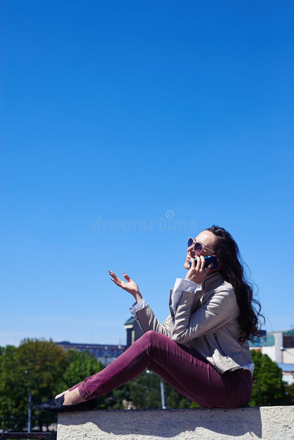 Appealing Lady Talking on the Phone while Sitting on Border Stock Photo ...