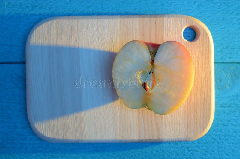 Apple Cuted in Half on a Wooden Board on Turquoise Table with a Long ...