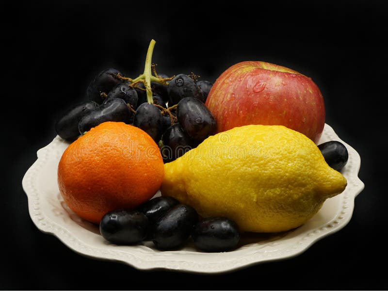 Apple, Lemon, Orange and Bunch of Grapes on White Plate Stock Photo ...