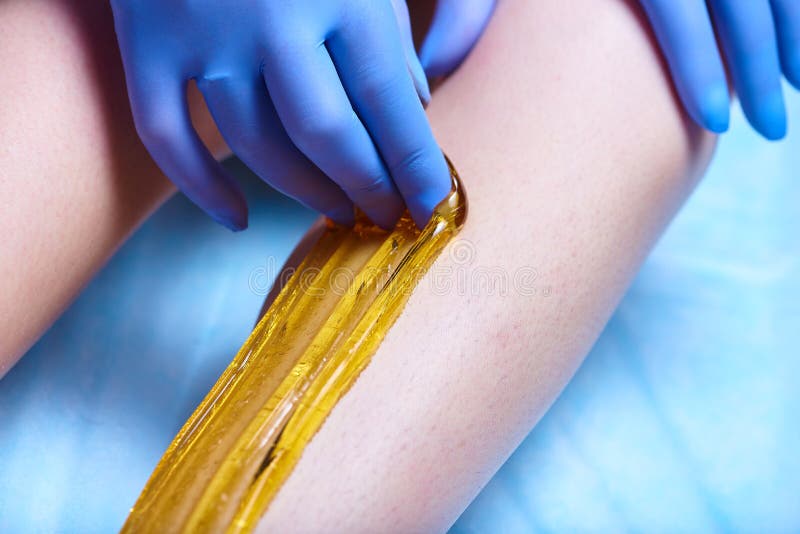 An Application of Golden Clear Sugaring Paste on a Leg with Hand in ...