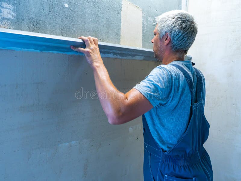 Applying Plaster Putty To the Wall Using a Aluminum Paver Screed. Stock ...