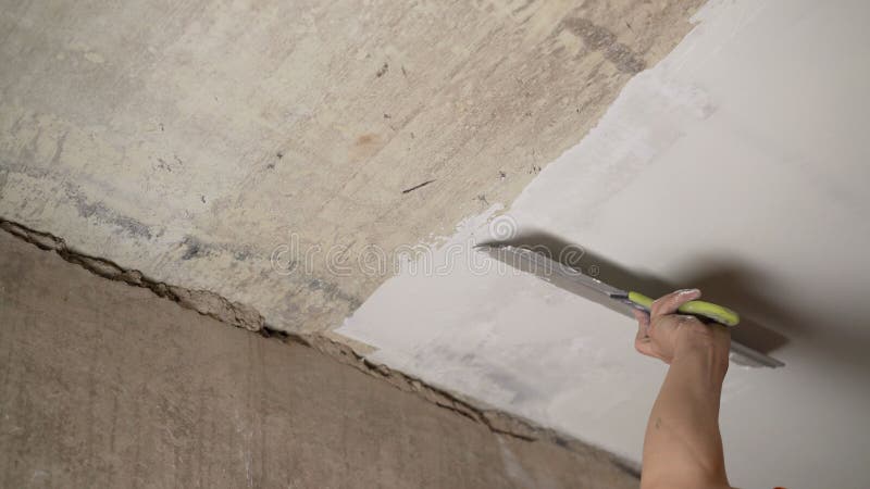 Hand with a Putty Knife and Putty, Apply Mastic To the Ceiling To Level ...