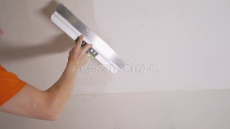Hand with a Putty Knife and Putty, Apply Mastic To the Ceiling To Level ...