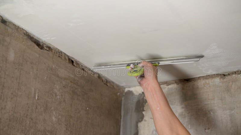 A Man Puts Putty on the Ceiling during Renovation Work. Hand with a ...
