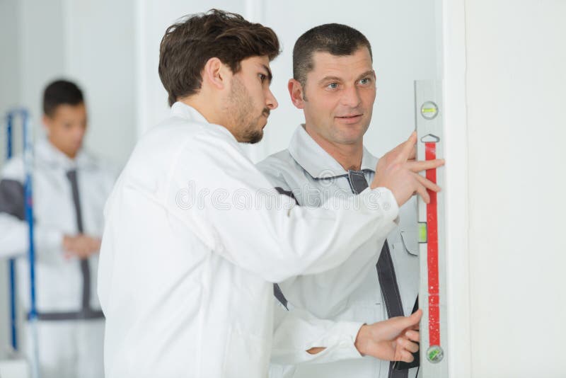 Apprentice Builder with Foreman Using Spirit Level Stock Image - Image ...