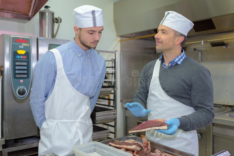 Apprentice and Chief Preparing Meat in Restaurant Kitchen Stock Photo ...