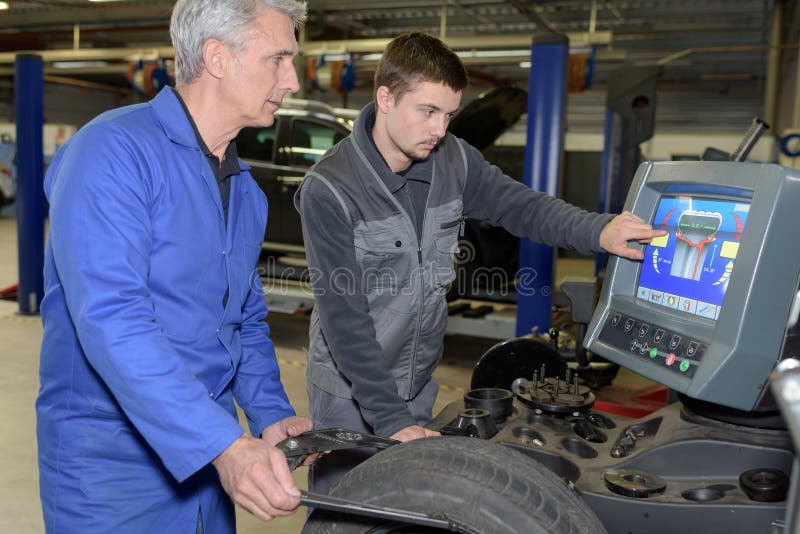 Apprentice Mechanic and Teacher Retreading Wheel in Automotive Workshop ...