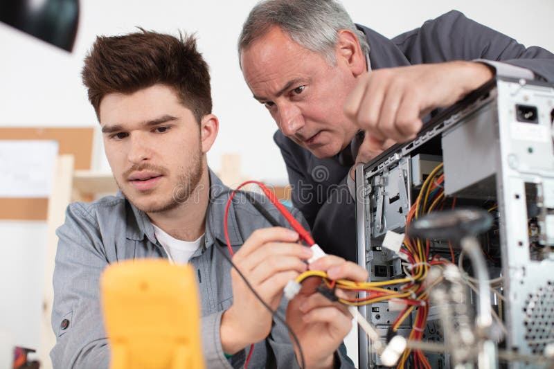 Apprentice Under Supervision Testing Computer with Multimeter Stock ...