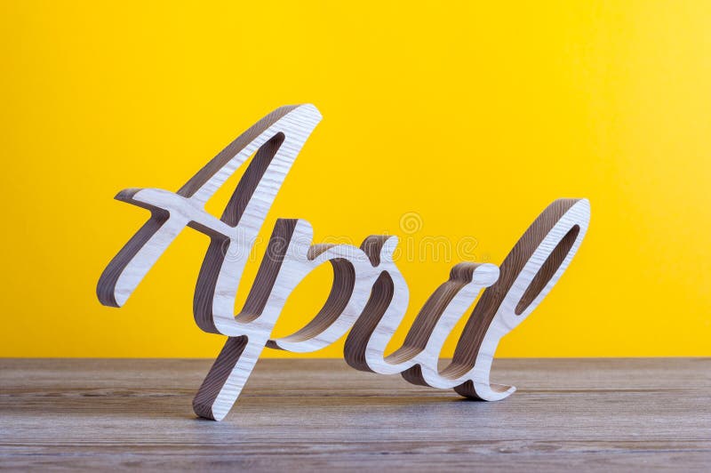 April - Wooden Carved Word on Yellow Background. Spring Time, 1st of ...