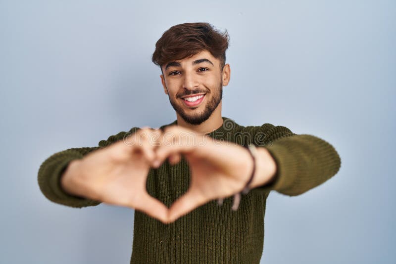 Arab Man with Beard Standing Over Blue Background Smiling in Love Doing ...
