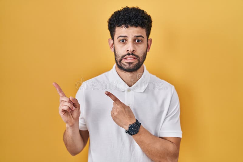 Arab Man Standing Over Yellow Background Pointing Aside Worried and ...