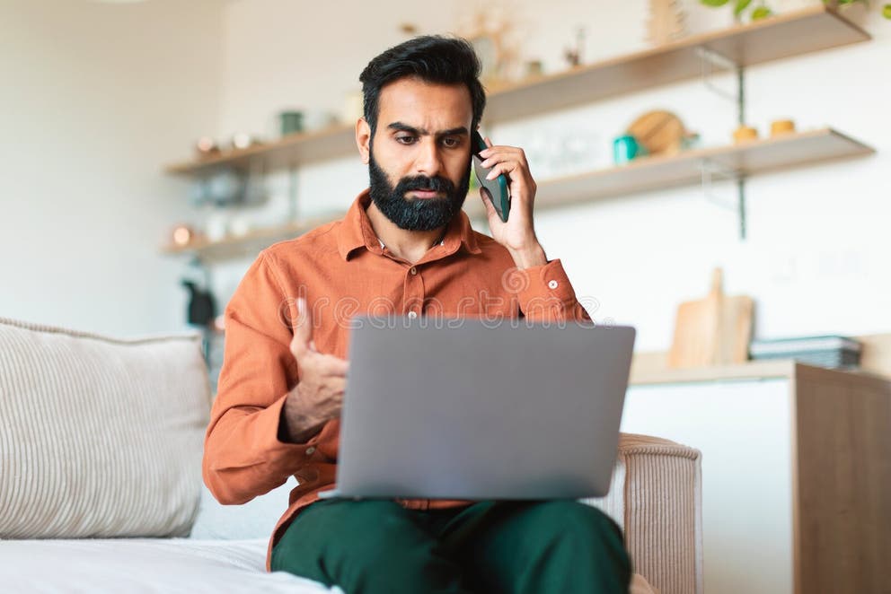 Arab Man Talking on Phone Using Laptop Expressing Discontent Indoor ...