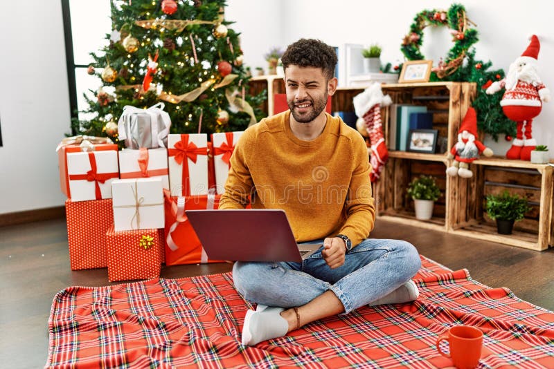 Arab Young Man Using Laptop Sitting by Christmas Tree Winking Looking ...