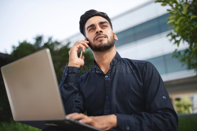 Arabian Businessman Using Laptop Computer and Talking by Phone Outside ...