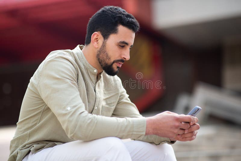 Arabic Man Sitting Outside and Looking at Mobile Phone Stock Image ...