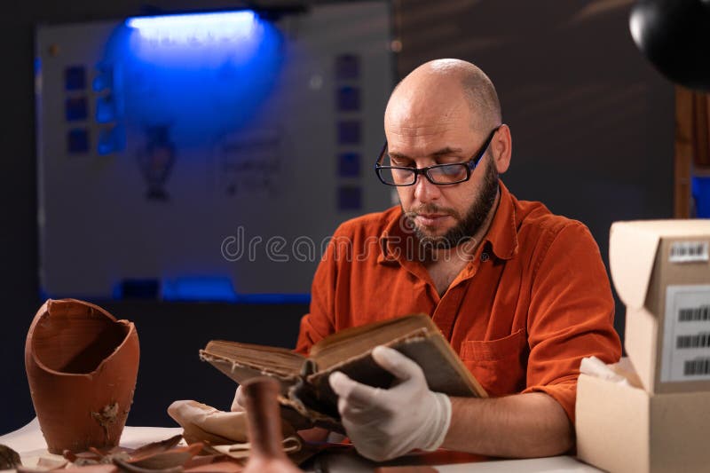 Archaeologist Working Late at Night in the Office Reading an Old Book ...