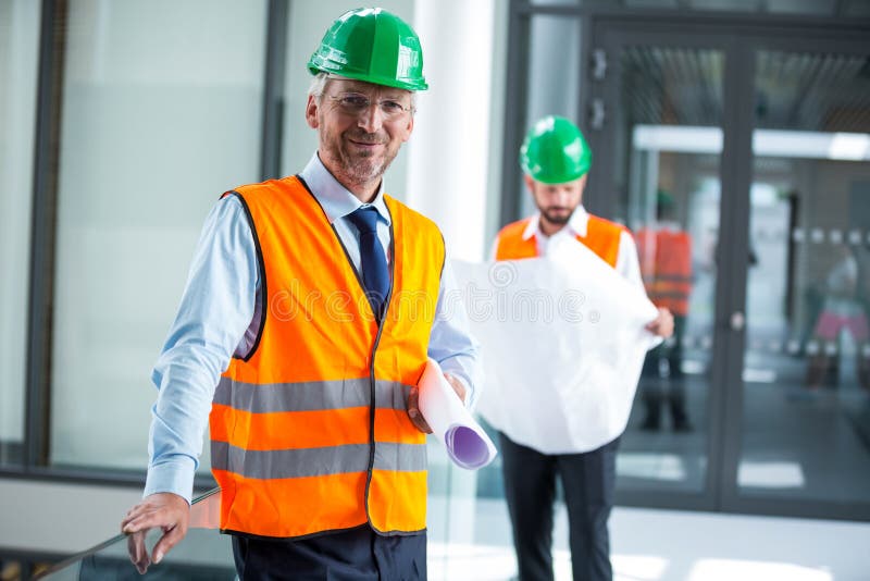 Architect in Hard Hat Standing with Blueprint in Office Corridor Stock ...