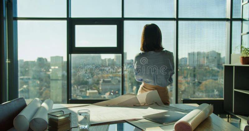 An Architect Standing by a Window Overlooking a Cityscape, Reflecting ...