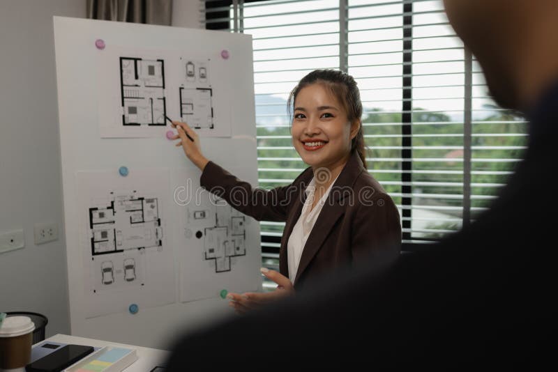 An Architect is Working in the Office with His Team, Blueprint on the ...