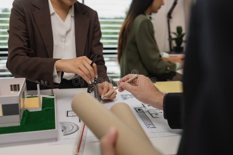 An Architect is Working in the Office with His Team, Blueprint on the ...