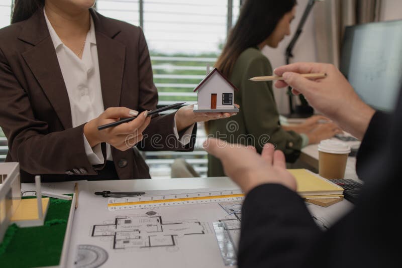 An Architect is Working in the Office with His Team, Blueprint on the ...