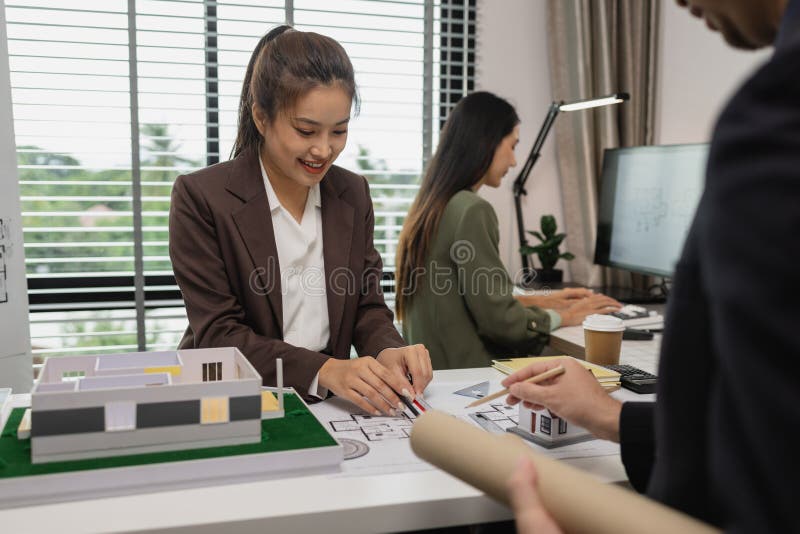 An Architect is Working in the Office with His Team, Blueprint on the ...