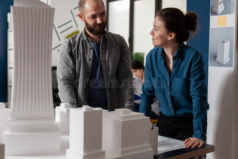 Architects Doing Teamwork Looking at Each Other Discussing Blueprints ...