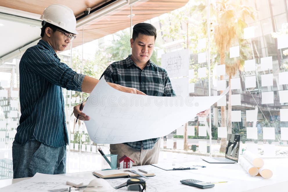 Architects or Engineering Working with Blueprints and Discussing Project Together at the Meeting ...